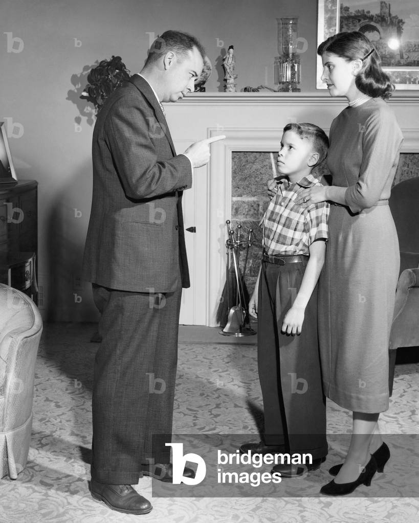 Image of Boy standing with his mother and being scolded by his