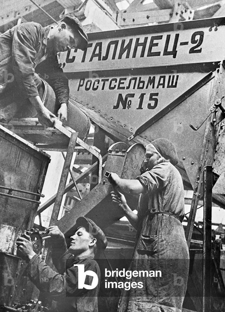 Image of Men and women at work on a combine harvester in by Russian ...