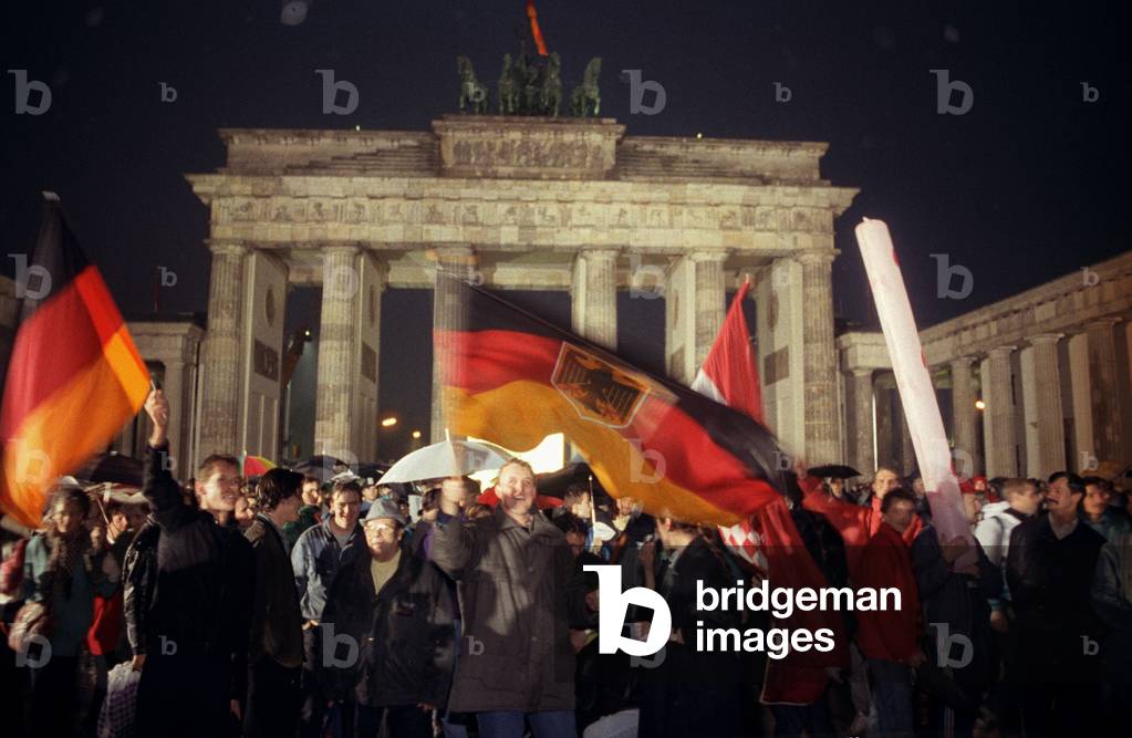 Image of Crowds wave German flags under the Brandenburg Gate, Berlin, 22