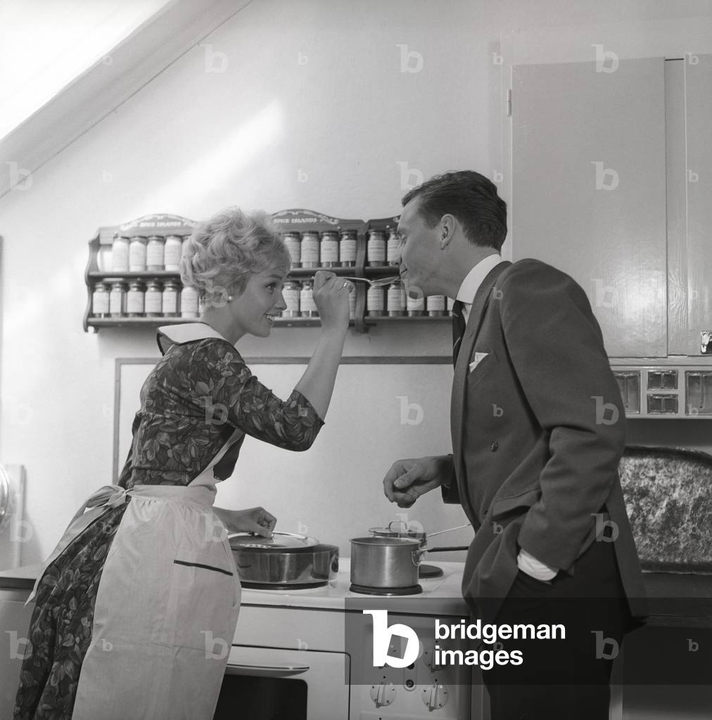 A young couple in their kitchen, 1950s (b/w photo) by