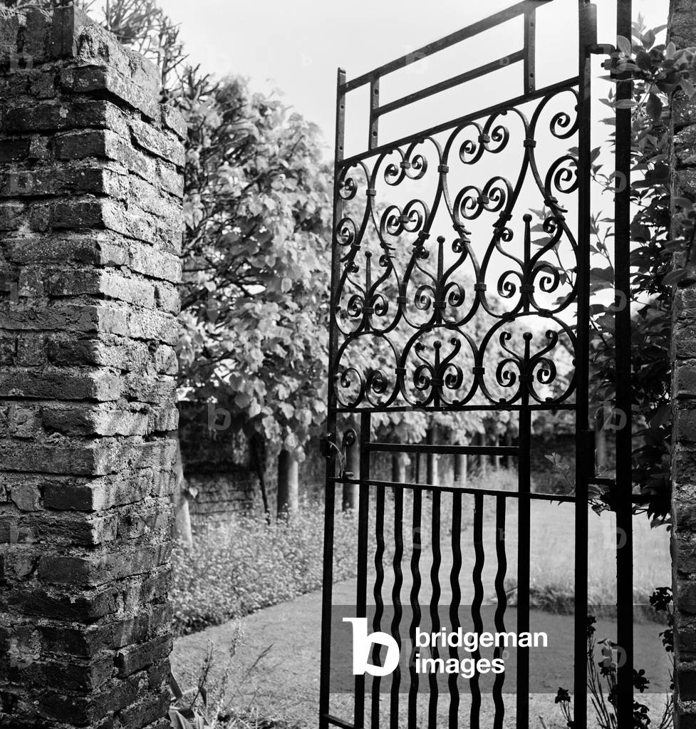 Image of A decorative wrought-iron gate with brick gate piers stands ...