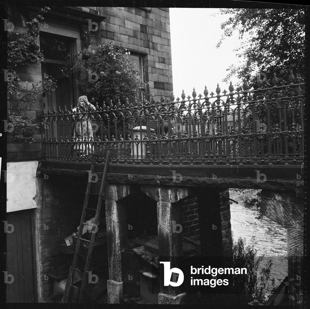 Image of A woman standing on the footbridge linking the house at
