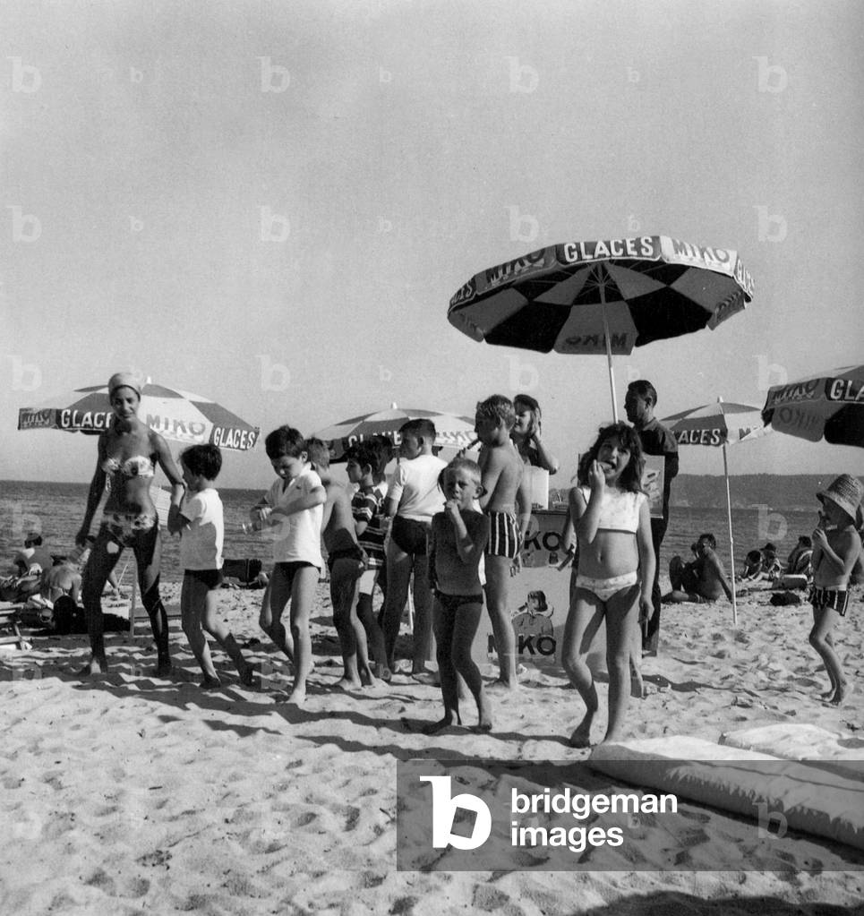 Image of Children eating ice cream cones at the beach in a