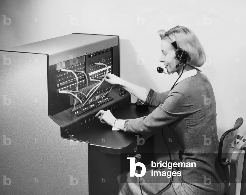 Image of Female switchboard operator operating a telephone switchboard
