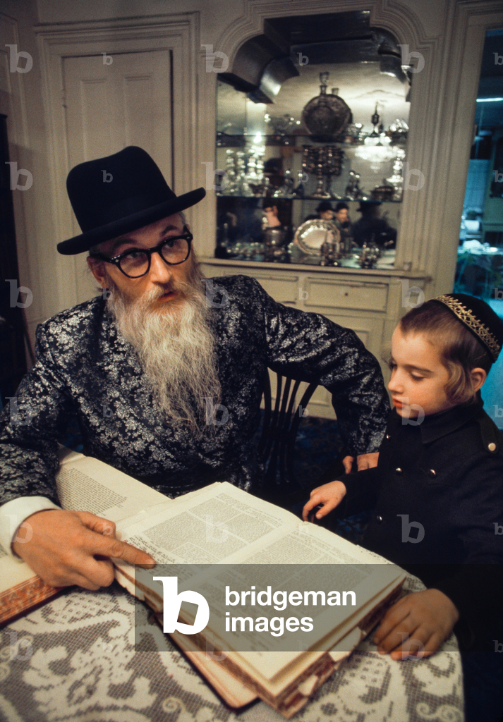 Image of Photograph of a rabbi teaching his son in their home by Benn ...
