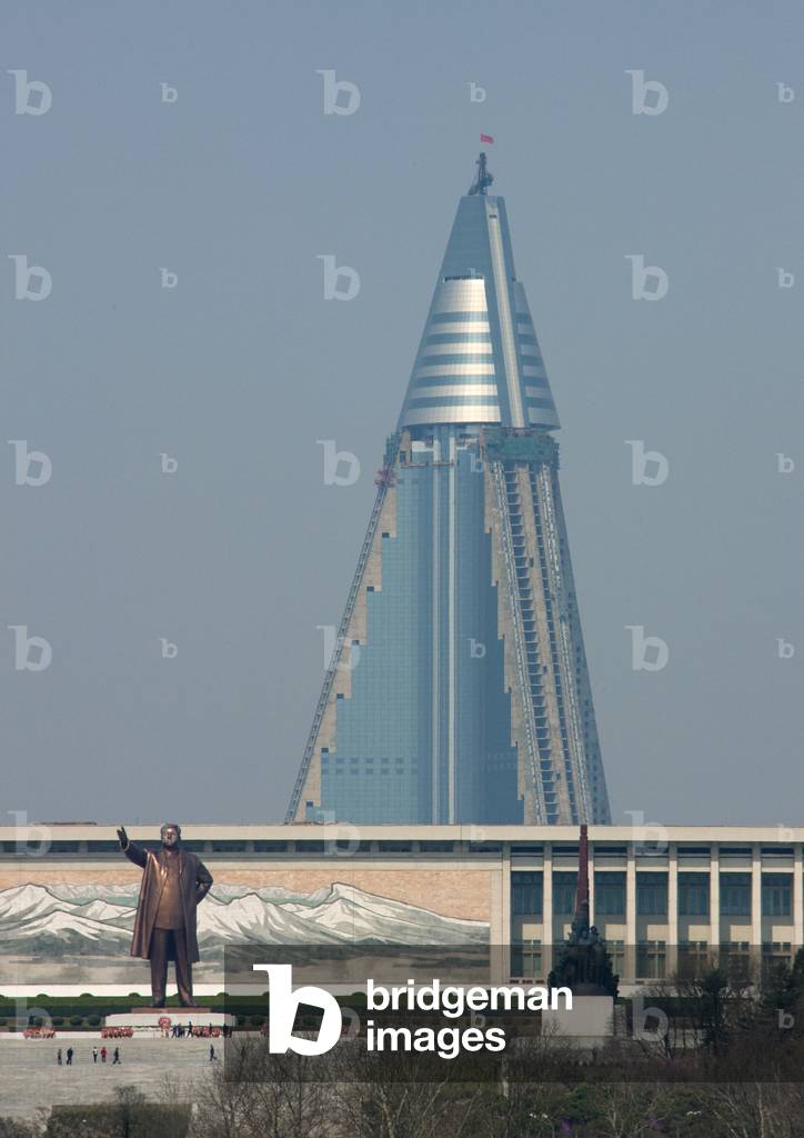 Image of Kim il Sung statue in front of the pyramid-shaped Ryugyong
