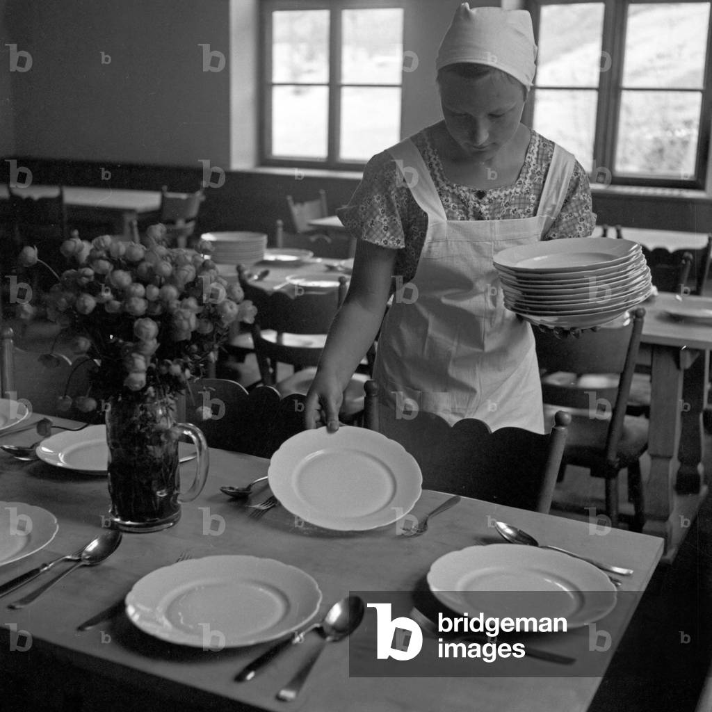 Image of A BdM girl laying the table at the dining hall
