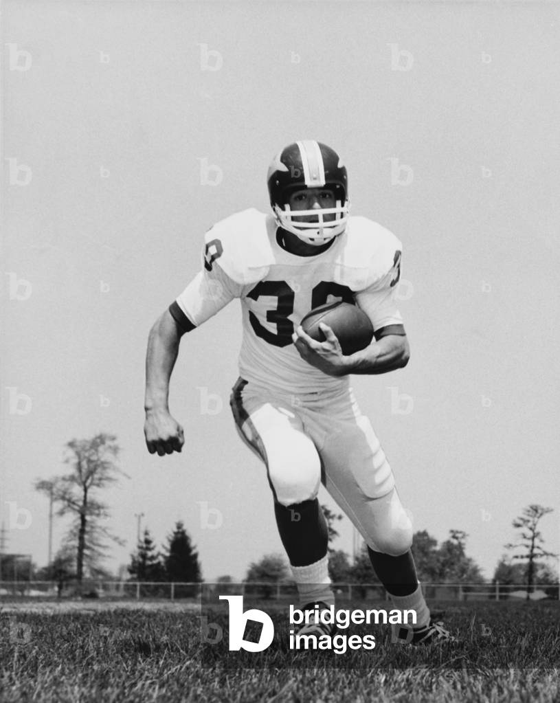 Image of Football player running with a football on a football field