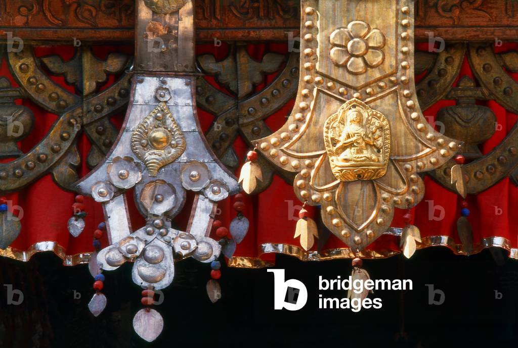 Nepal: Wood and metal dhvaja (banner or flag) hang from an eave at a ...