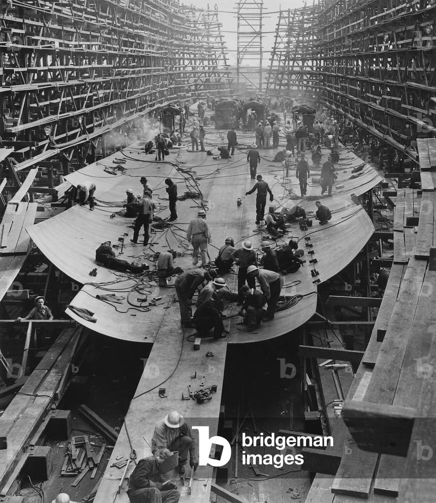 Image of American war workers laying down the hull of a Liberty