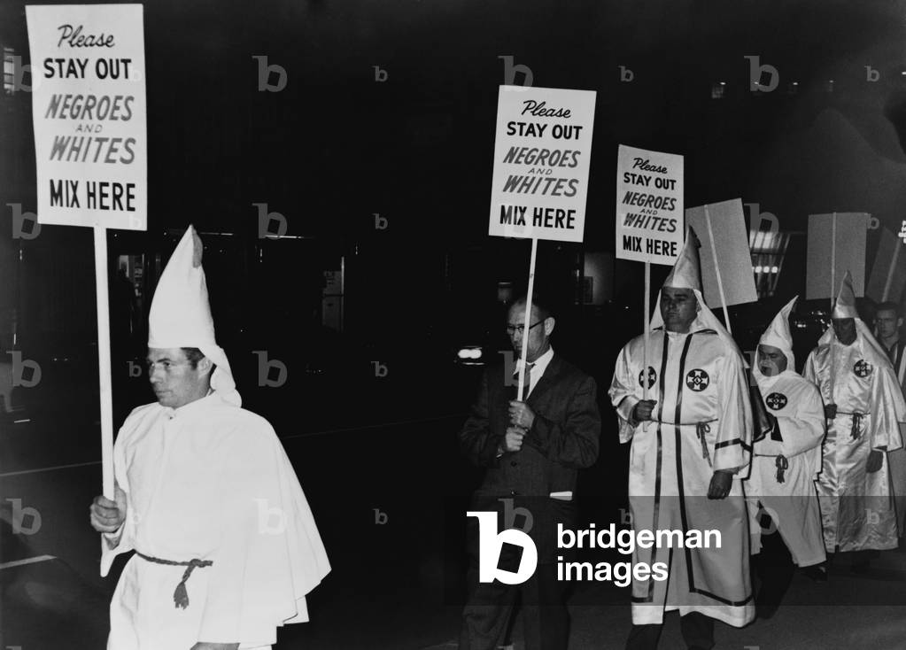 Image of Ku Klux Klan members, in hooded white robes hoods, picket