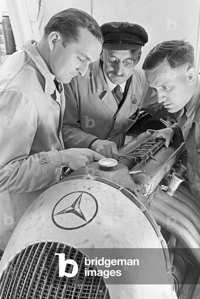Image of The racing driver Hermann Lang talking to car mechanics in