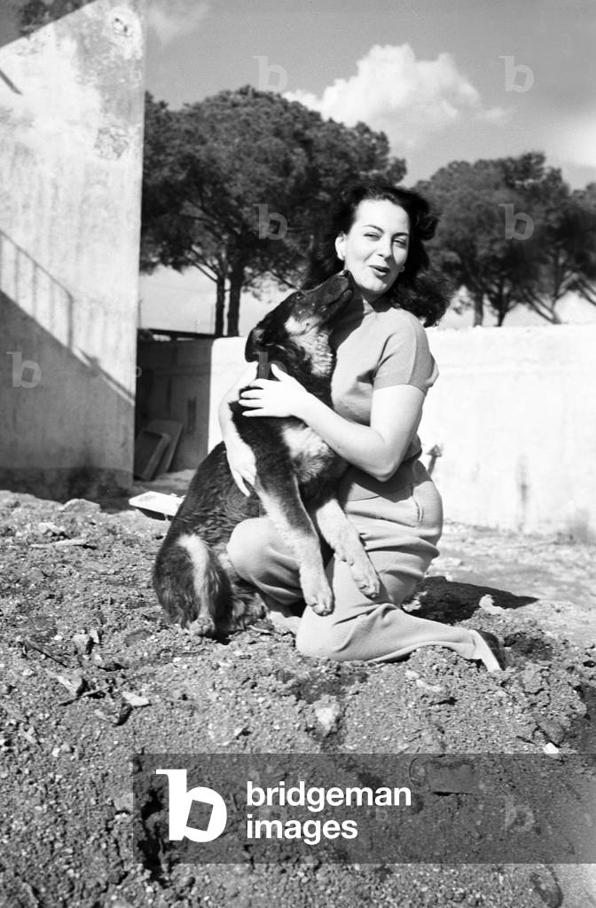 Image of Yvonne Sanson hugging her dog, Italy, 1951 (b/w photo)