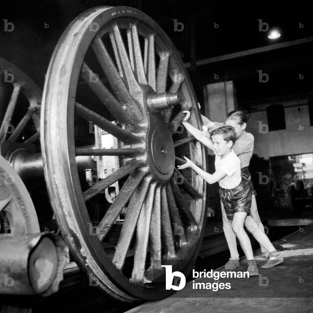 Image of Two boys with a drive wheel of a steam engine