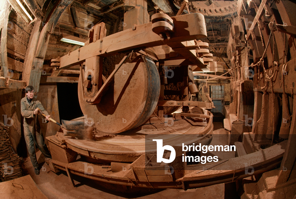 Image of A man grinds cacao bean shells for animal feed in by Stanfield ...