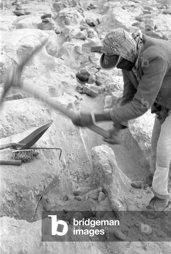 Image of A worker digging with a pick into a diamond mine,