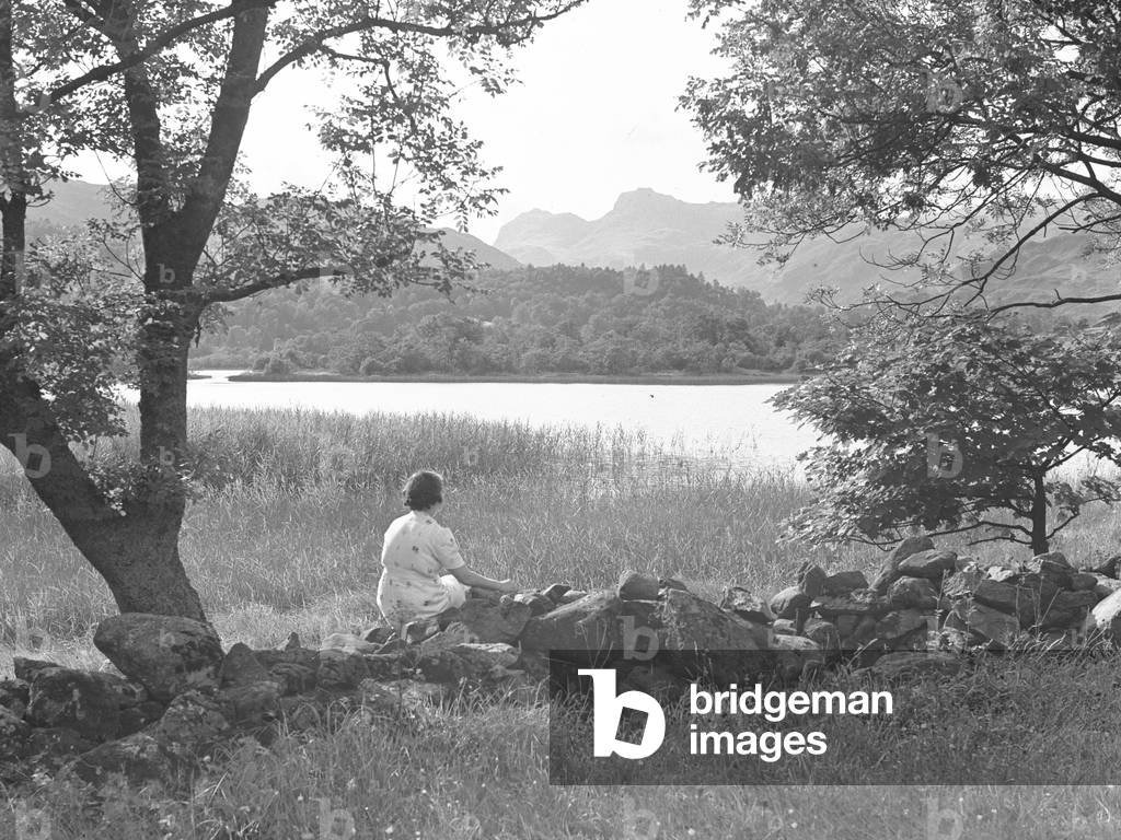 Image of Woman sitting on collapsed stone wall with back to camera by ...