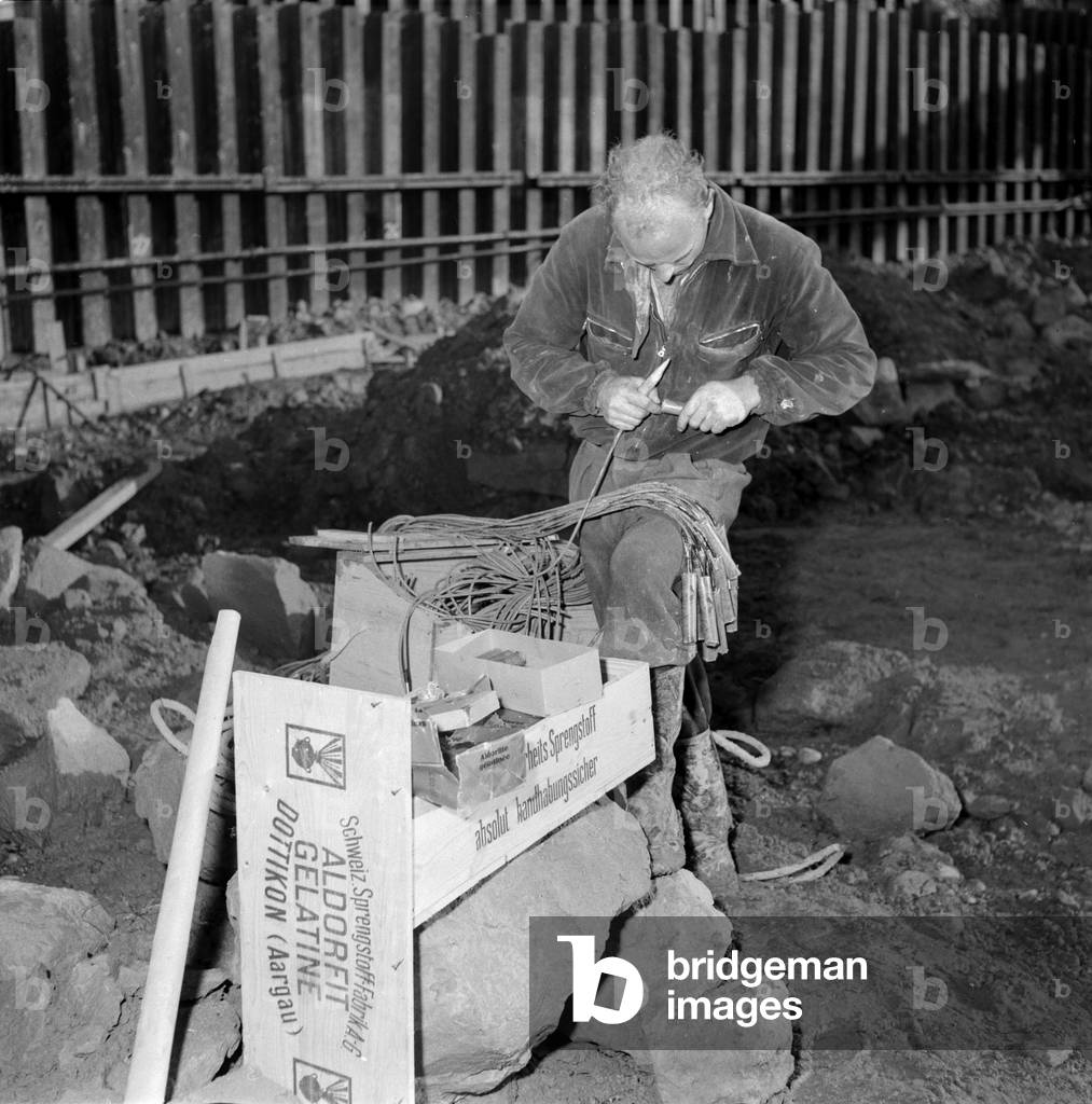 Image of A construction worker prepares explosive charges on the ...